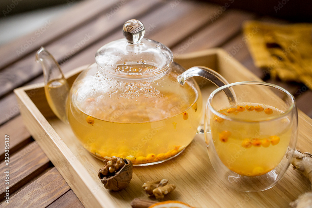 Sea buck thorn tea in glass teapot with glass cup and spoon, orange and ...