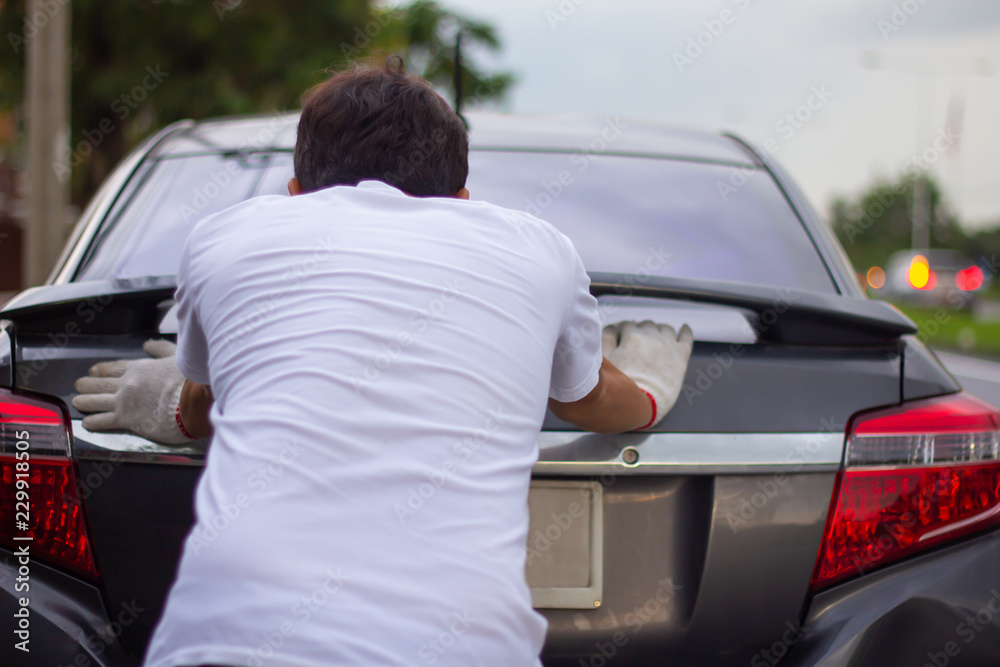 Mechanic man pushing a broken car down the road back view. Stock Photo ...