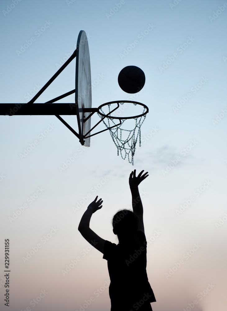 Silhouette of a young girl shooting a basketball Stock Photo | Adobe Stock