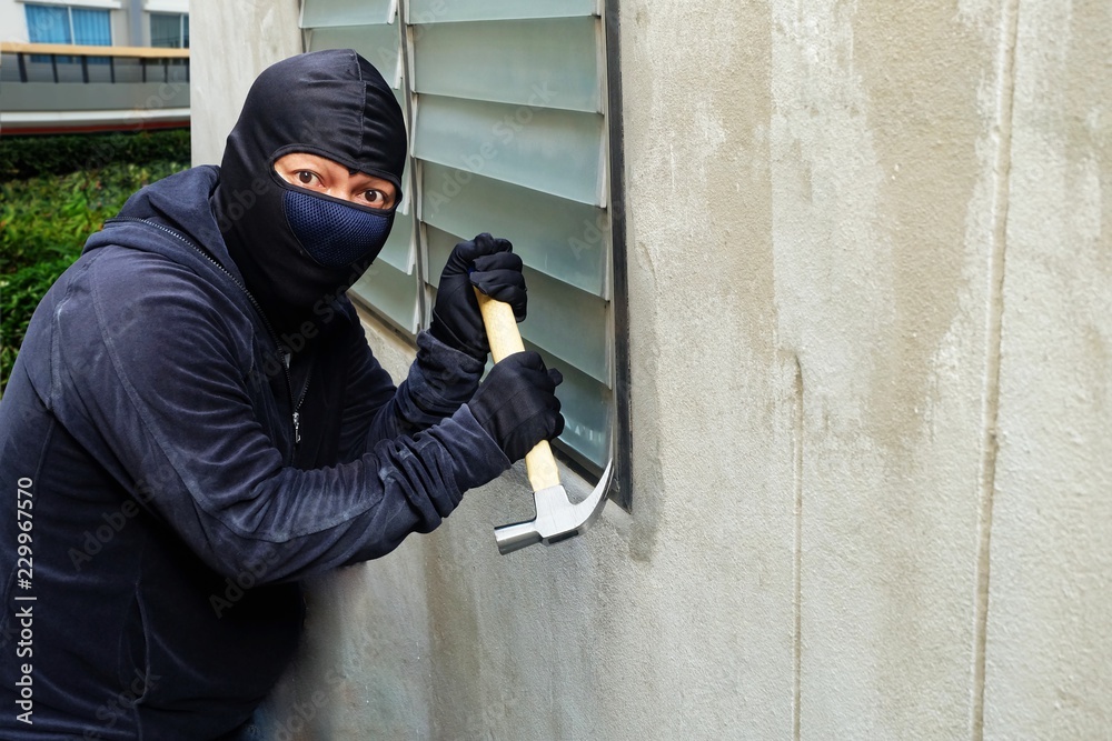Masked thief using a hammer trying to break windows and the Shocked ...