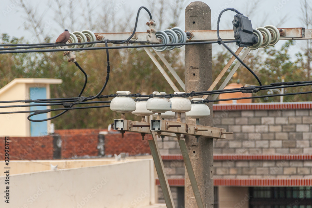 Heavy duty power lines are held up by white insulators attached to ...