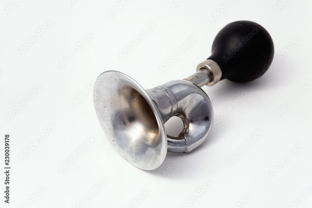 A worn iron horn or klaxon from a vintage car or bicycle lies ...