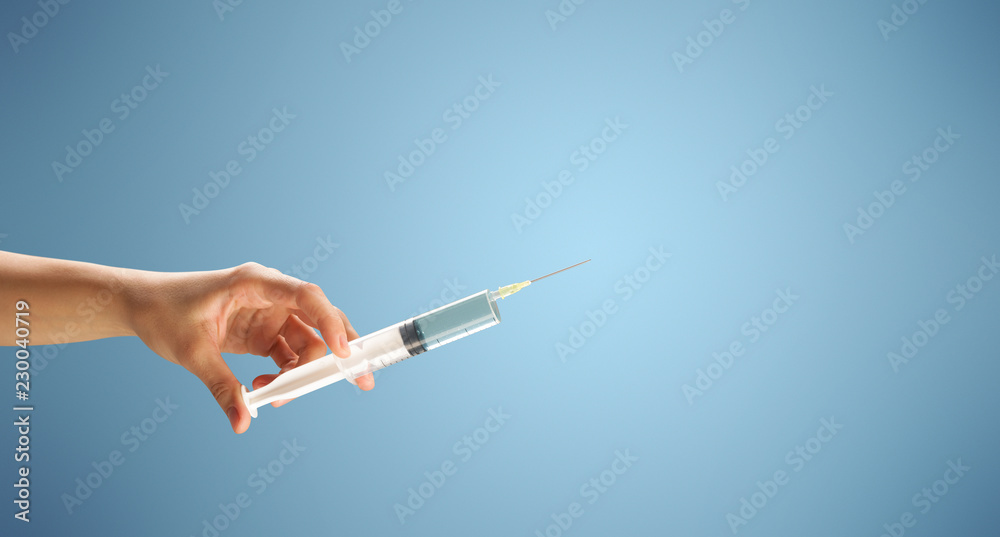 Female doctor hand holding syringe with blue background Stock Photo ...