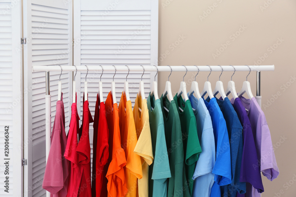 Rack with bright clothes in room. Rainbow colors Stock Photo | Adobe Stock