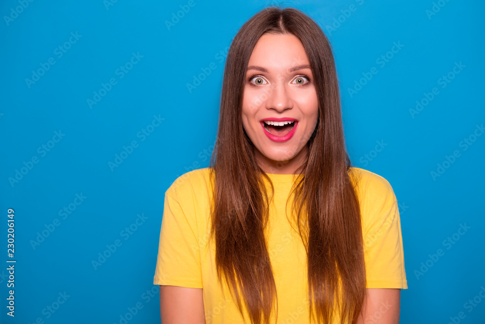 Cute brunette woman with long hair posing in yellow t-shirt on a blue ...