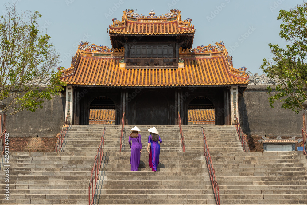 Traditionally dressed Vietnamese young women climb the stair of ...