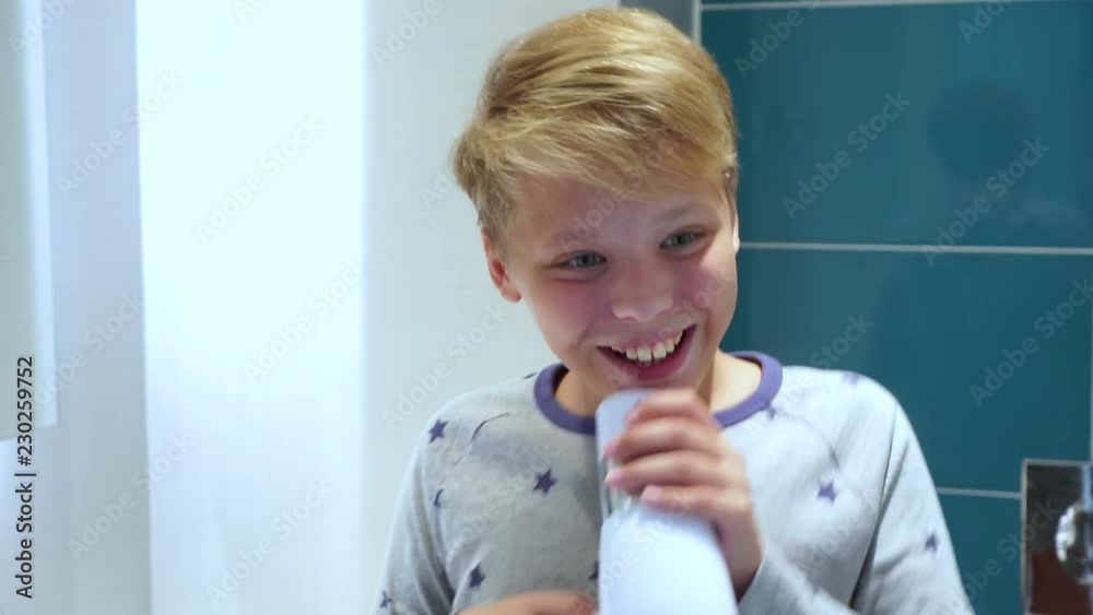 Front view of happy cute little boy sings song in bathroom using hair ...