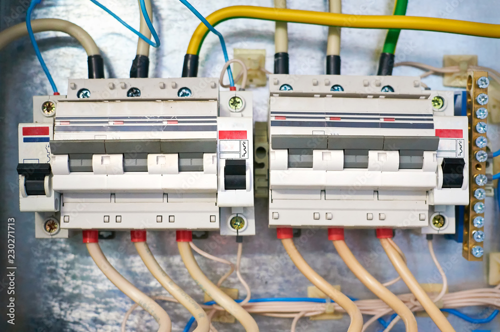 Two electric three-phase switches connected by wires on a metal ...