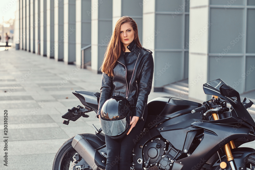 A Beautiful Biker Girl Holding Helmet While Leaning On Her Superbike