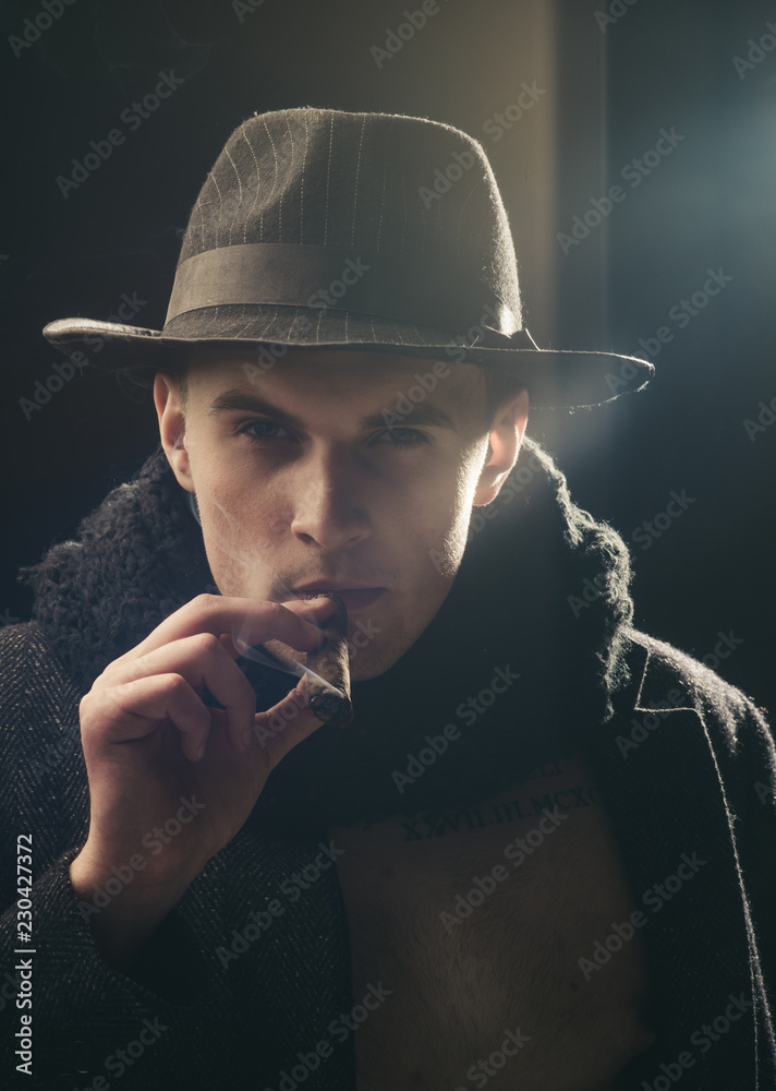 Vintage detective concept. Man in coat, hat smoking cigar, dark ...