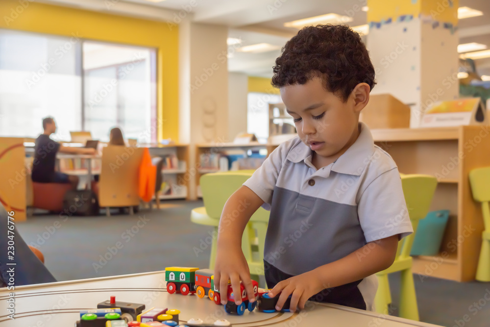 Little boy plays with a wood train set at the community library. Stock ...