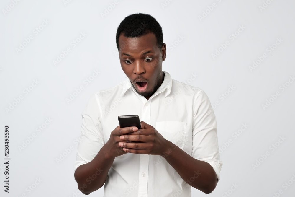 African Man Looking At Phone Seeing Shocking News Or Photos With