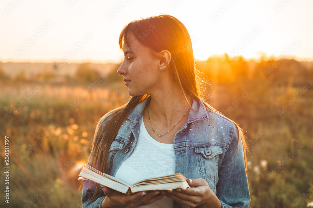Beautiful girl in autumn field reading a book. The girl sitting on a ...