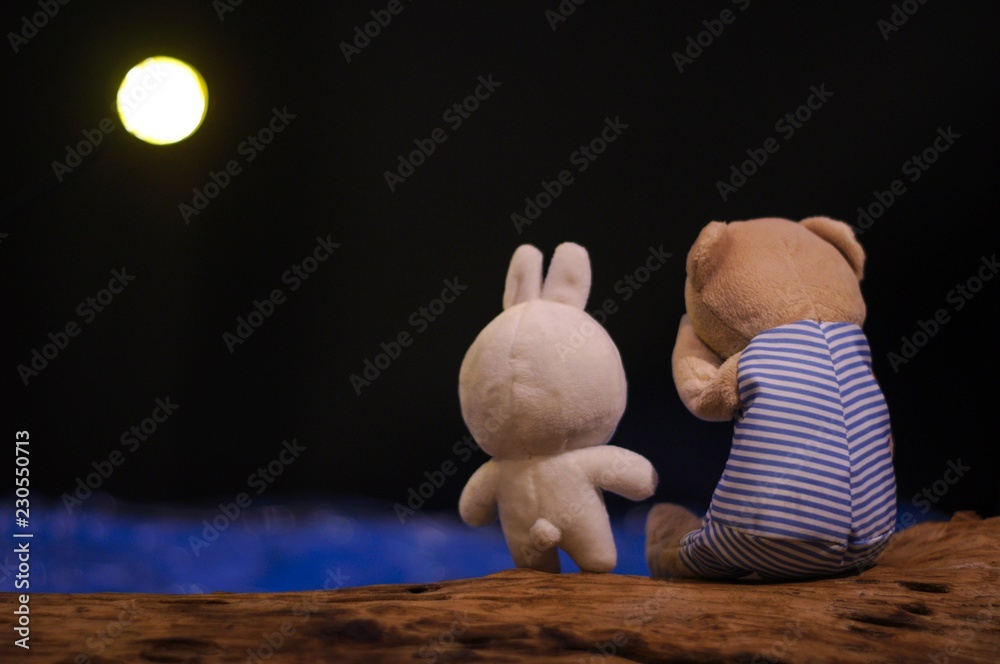 Teddy bear crying and sitting on a timber facing to the blue sea and ...
