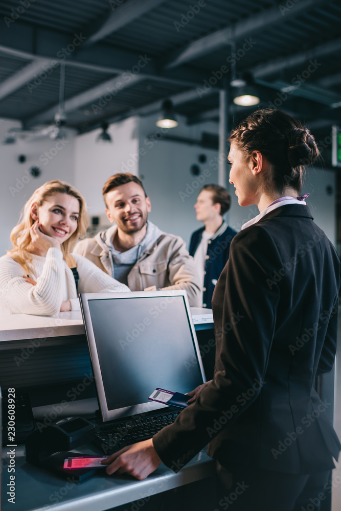 young airport worker checking documents at check-in desk in airport ...
