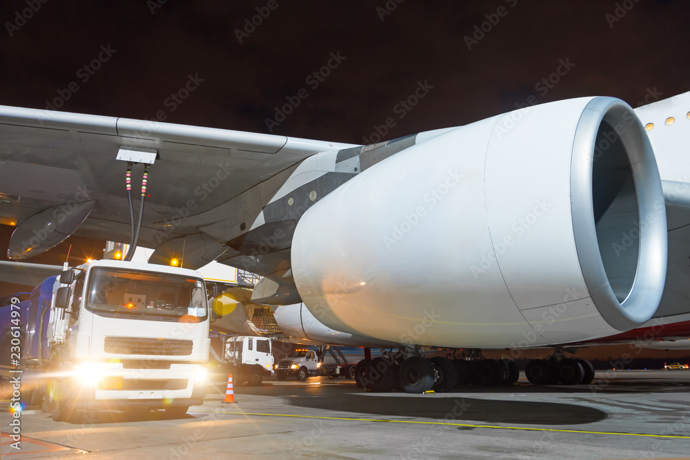 Fueling a huge aircraft, a truck with fuel with hoses connected to a ...