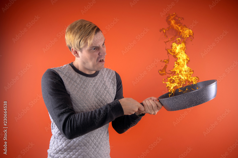 Emotional guy holding a frying pan in his hands, on an orange ...