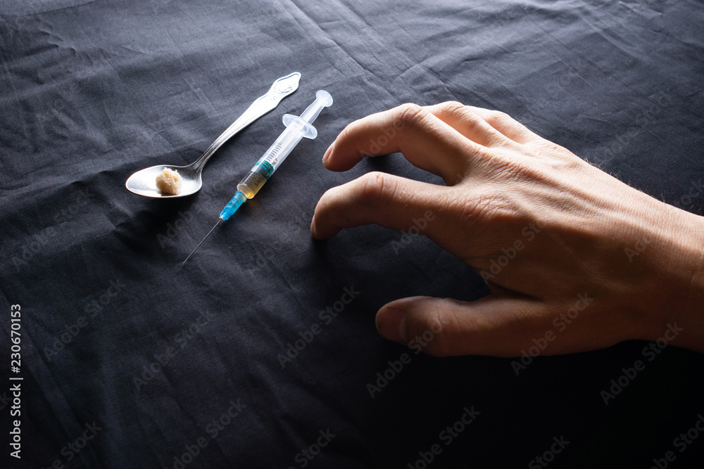 Syringe for injection filled with heroin and a spoon, hand addict, top ...