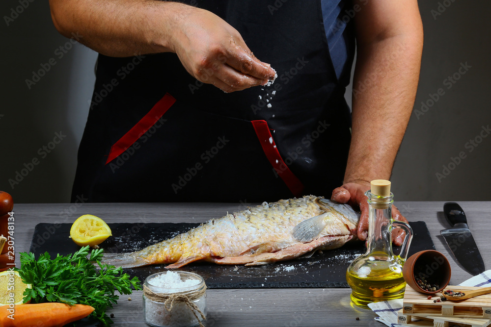 Chef salts fish, river carp. Preparing fresh fish. Horizontal photo ...