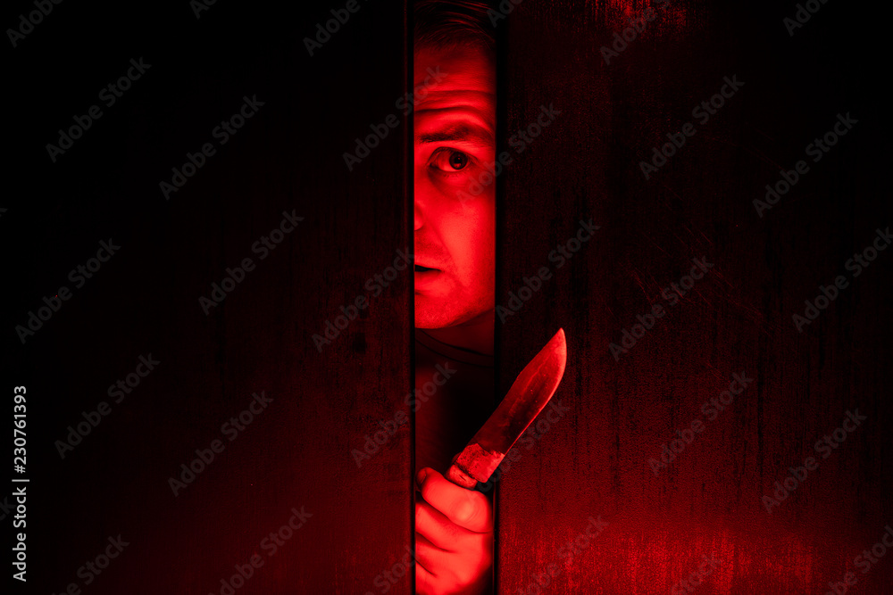 Fotografia do Stock: Serial killer / eye peeking behind the door with ...