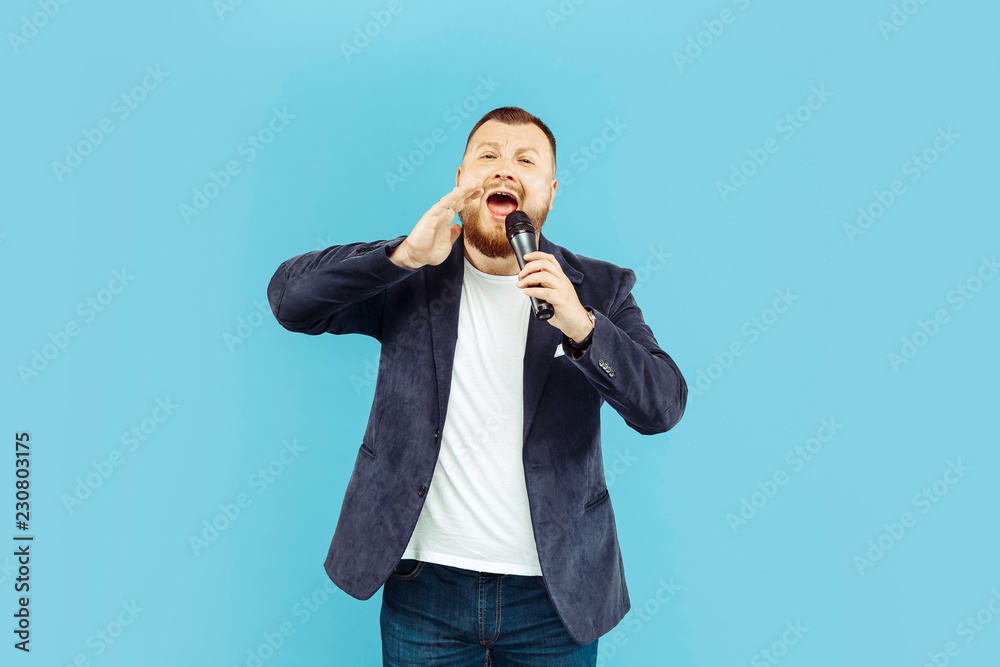 Young man with microphone on blue studio background, leading concept ...