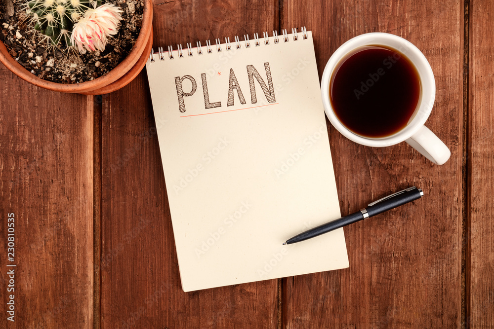 A photo of a spiral notepad with the word Plan, with a cup of coffee ...