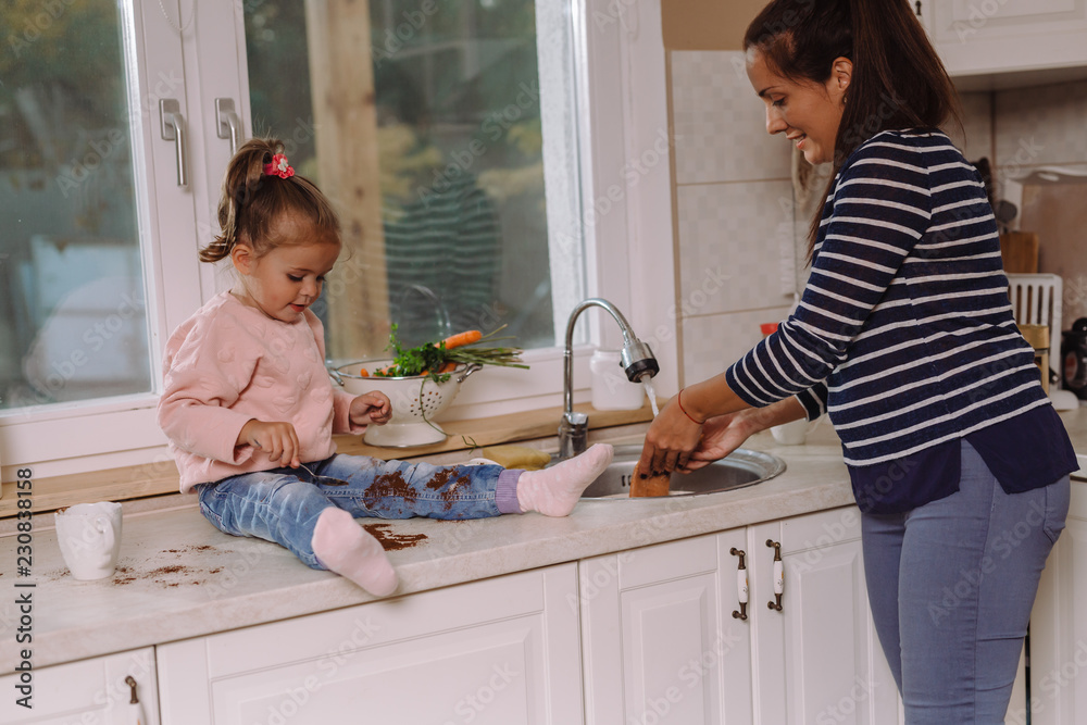 Little girl sitting on kitchen counter and making big mess in kitchen ...