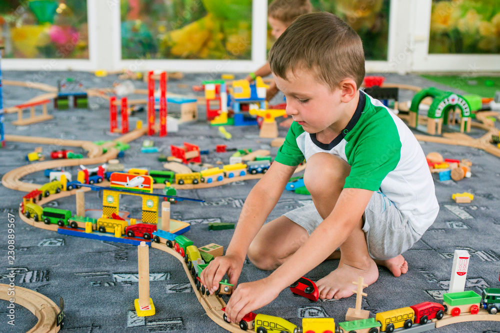 Little child playing with wooden railway on the floor. Little boy ...