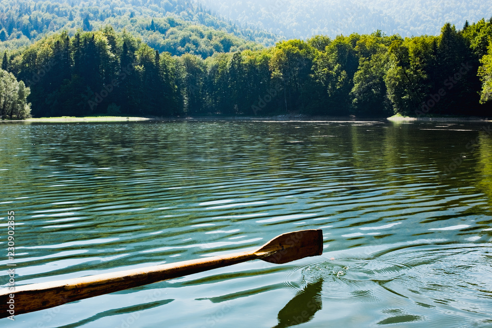 Oar of boat touching water and causing splash and ripples in the water ...