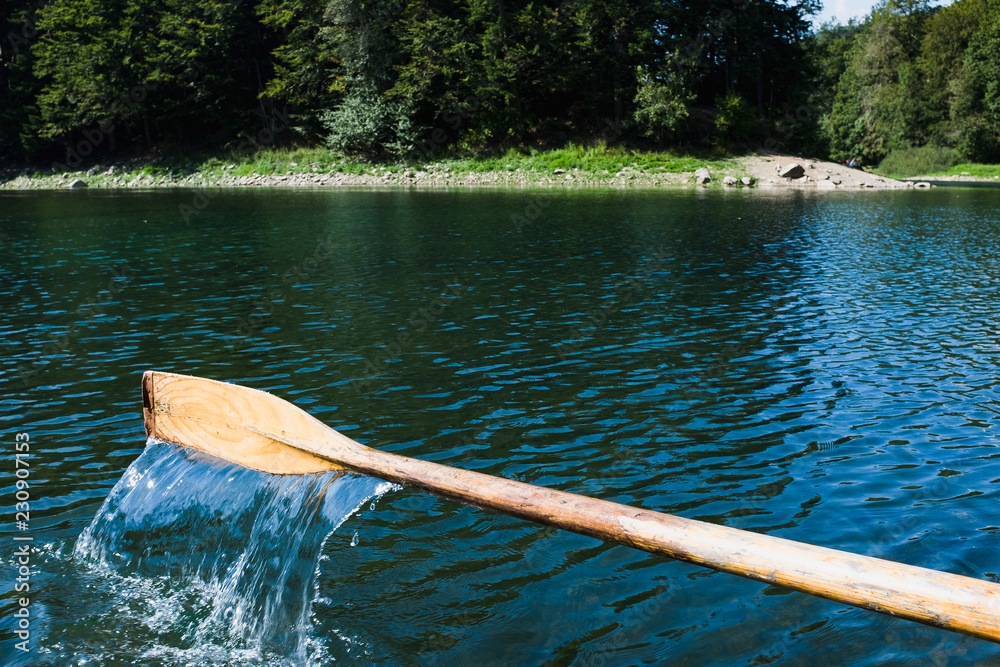 Oar of boat touching water and causing splash and ripples in the water ...
