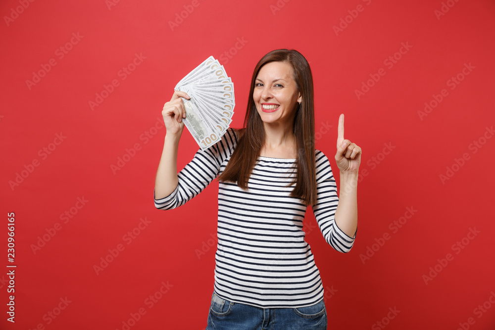 Beautiful young woman pointing index finger up and holding bundle lots ...
