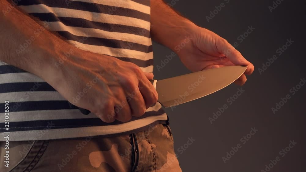 Evil man with shiny knife - a killer person playing with sharp knife ...