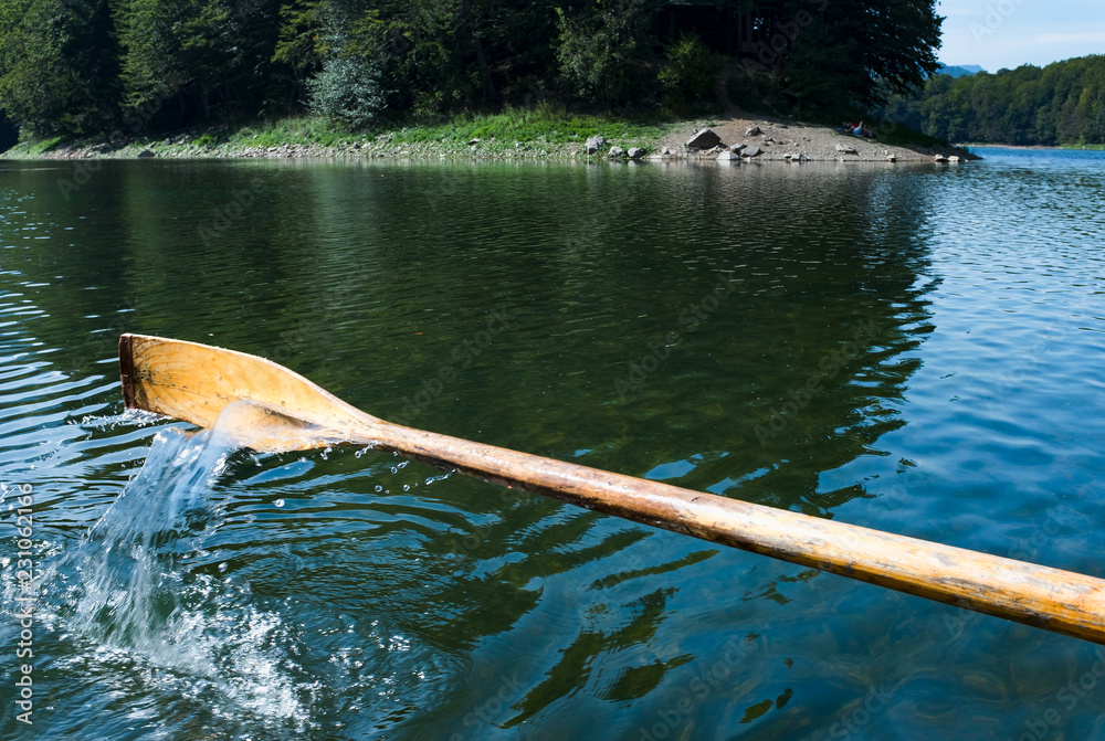 Oar of boat touching water and causing splash and ripples in the water ...
