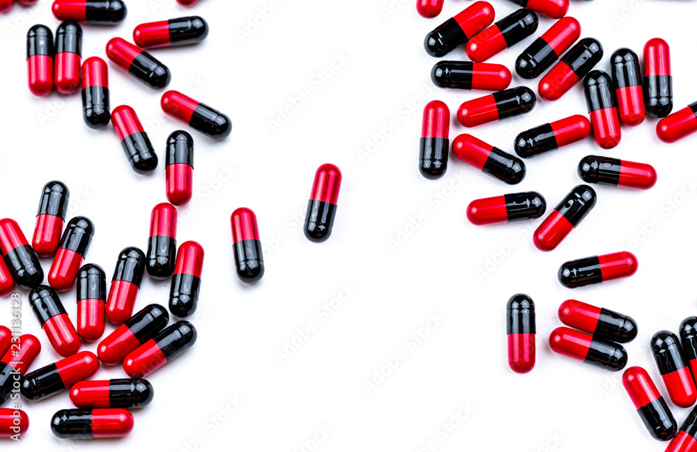 Red-black capsule pills spread on white background. Antibiotic drug use ...