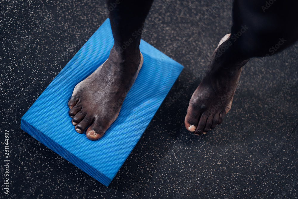 Feet correction and balance exercise. Black man using foam device in a ...