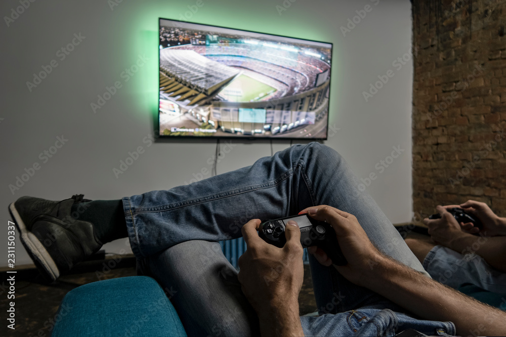 Two men playing video game. Hands holding console controller. Football ...