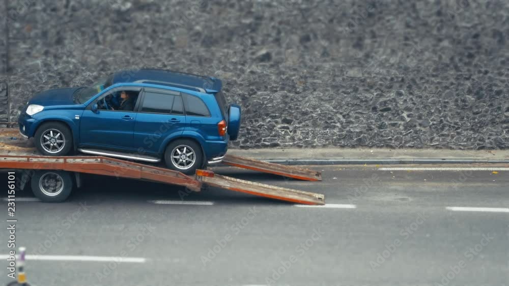 Tow truck takes broken suv. Young woman inside the car. Rescue roadside ...
