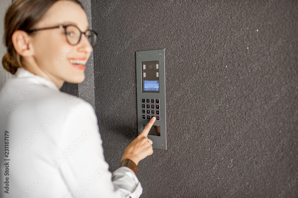 Young business woman in white suit entering code on the intercom ...