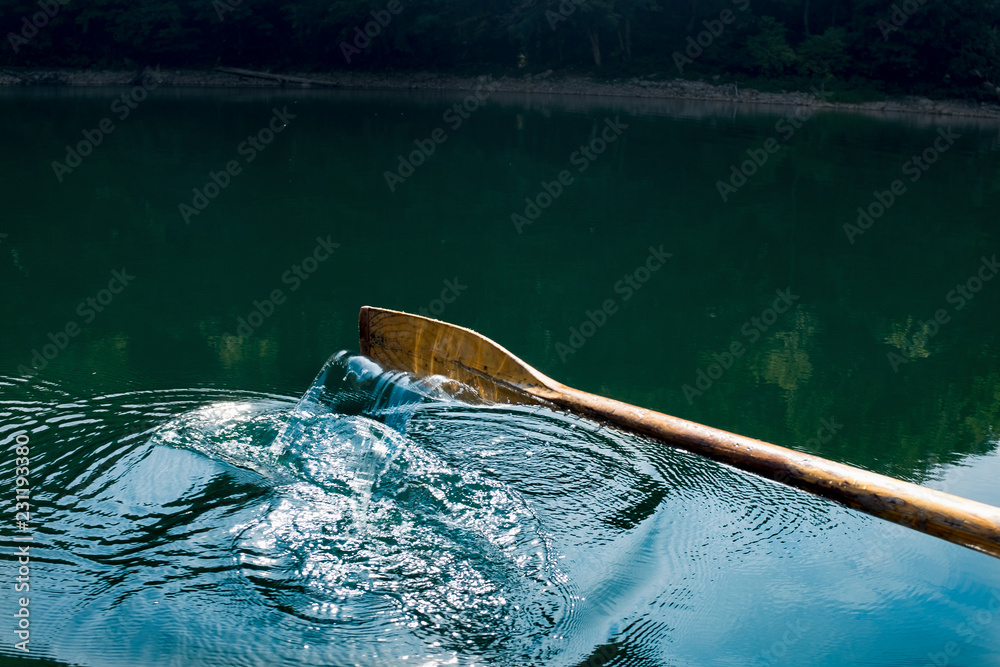 Oar of boat touching water and causing splash and ripples in the water ...