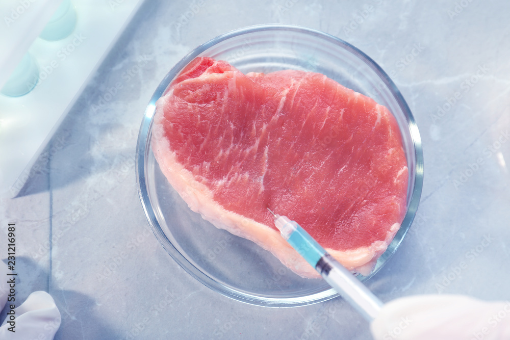 Scientist injecting liquid into meat sample on table, closeup. Food ...