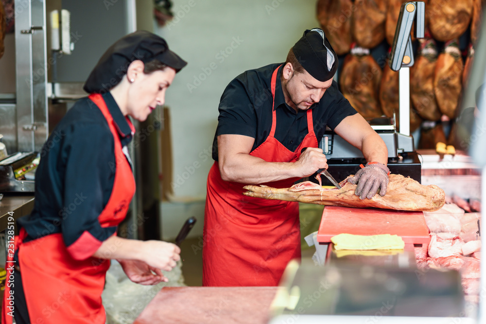 Butchers boning a ham in a modern butcher shop Stock Photo | Adobe Stock
