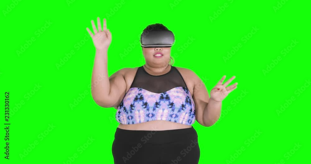 Overweight woman using a virtual reality headset while touching virtual ...
