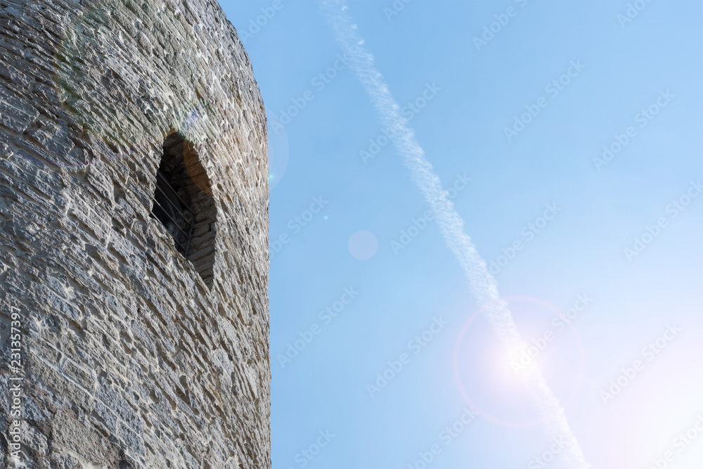 Part of the brick tower. Trace in the sky from the airplane. foto de ...