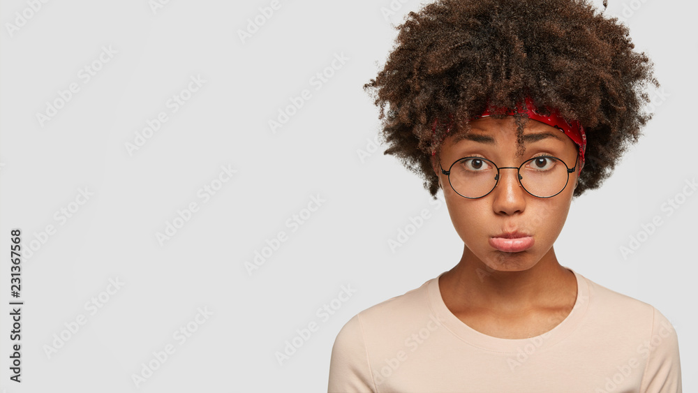 Indoor shot of dejected woman with dissatisfied expression, purses ...