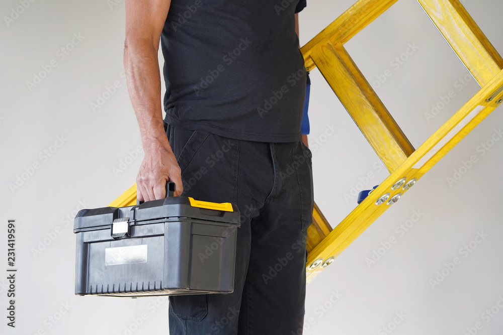 Electrician holds tool box and yellow wooden ladder. The builder ...