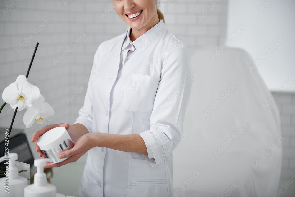 Cropped portrait of smiling cosmetologist in white lab coat holding ...