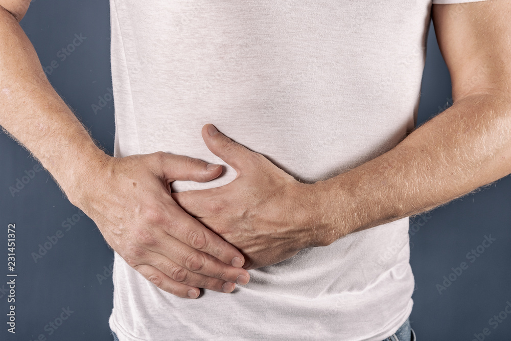 Man suffering from pain in his side. Blue background. Stomach, liver ...