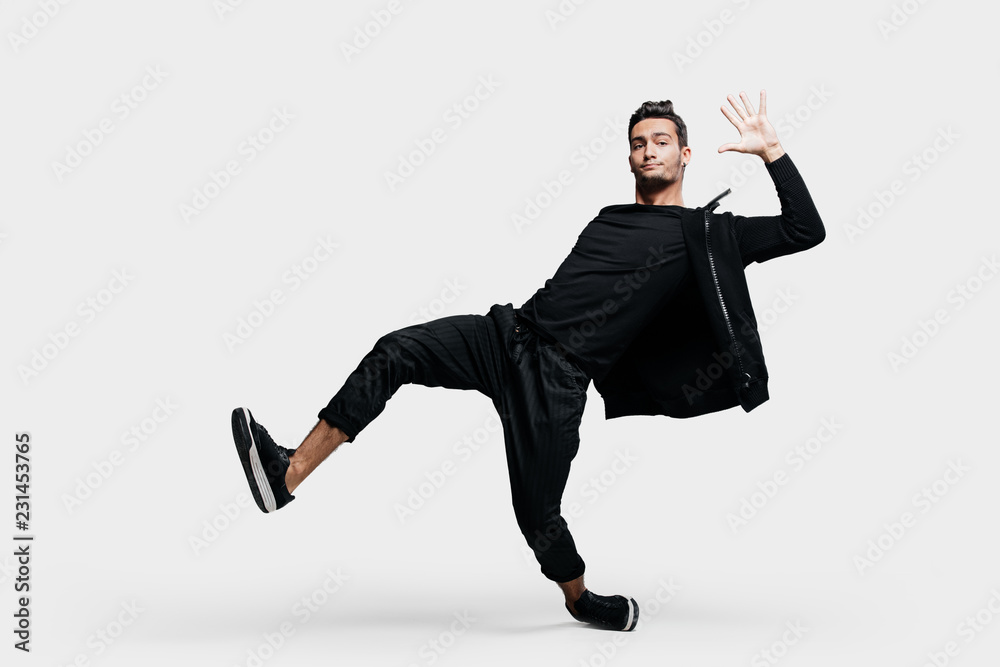 Handsome young man dressed in a black clothes is dancing street dance ...