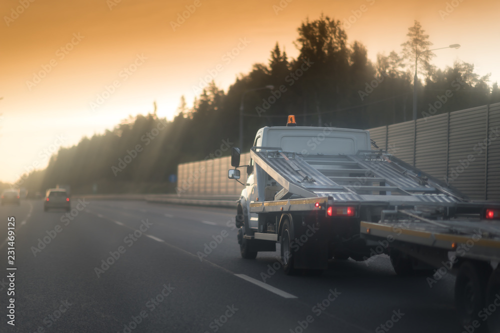 A white car hauler truck with an empty two-tiered trailer for ...
