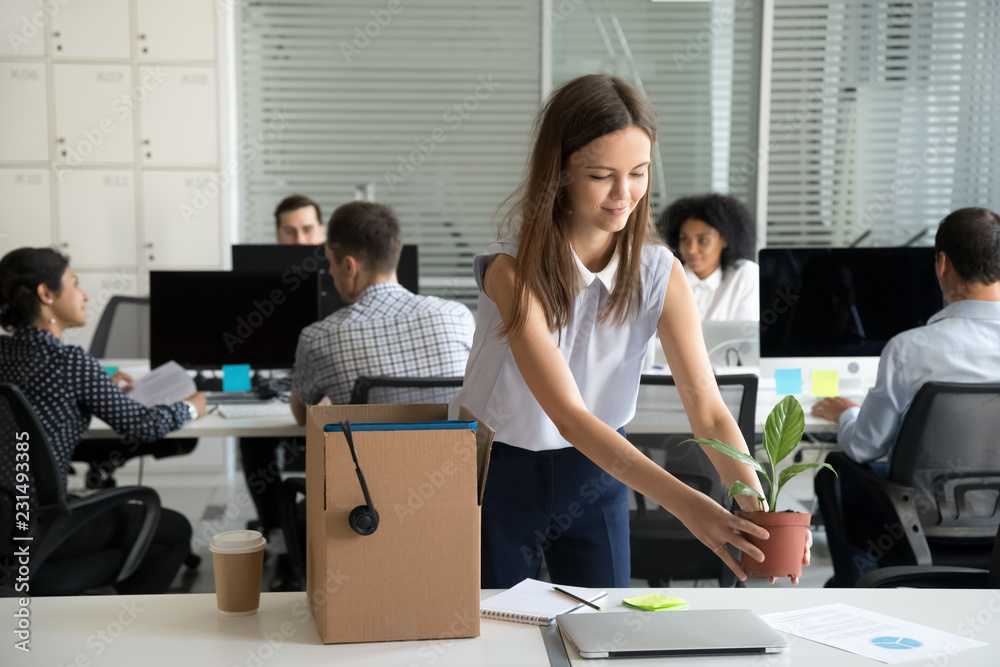 Smiling hired female company employee unpacking box with personal ...